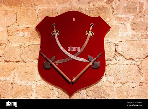 Swords and axes hung on the wall on a red velvet shield Stock Photo - Alamy