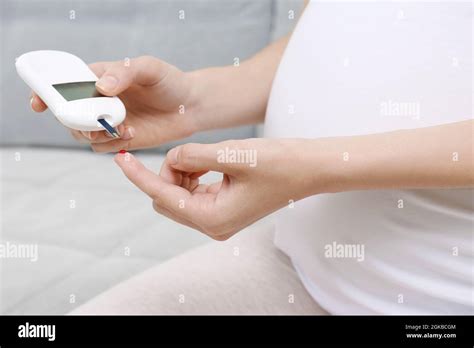 Pregnant woman testing glucose level with digital glucometer indoors ...